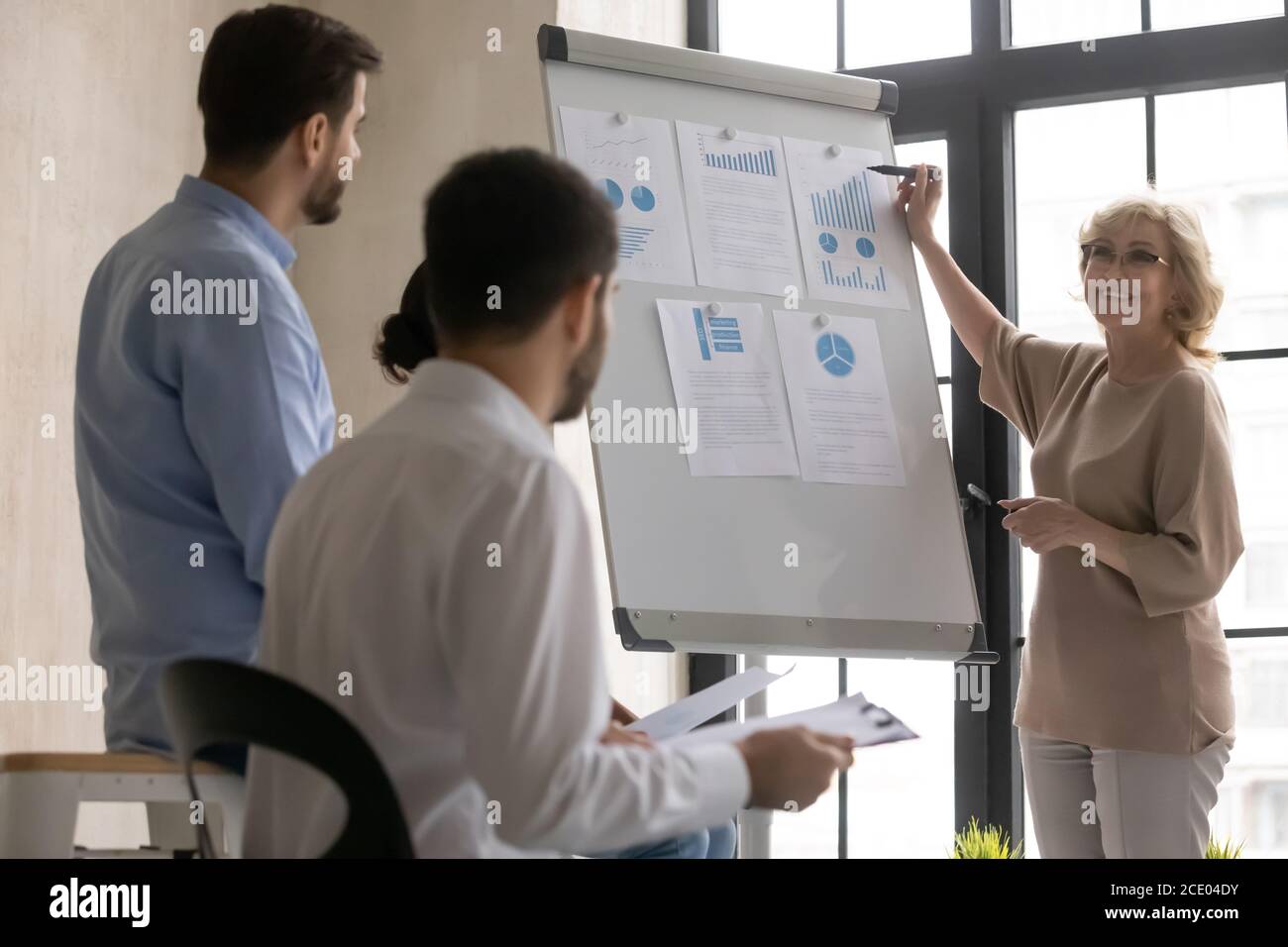 Happy middle aged female leader mentoring young multiracial sales team ...