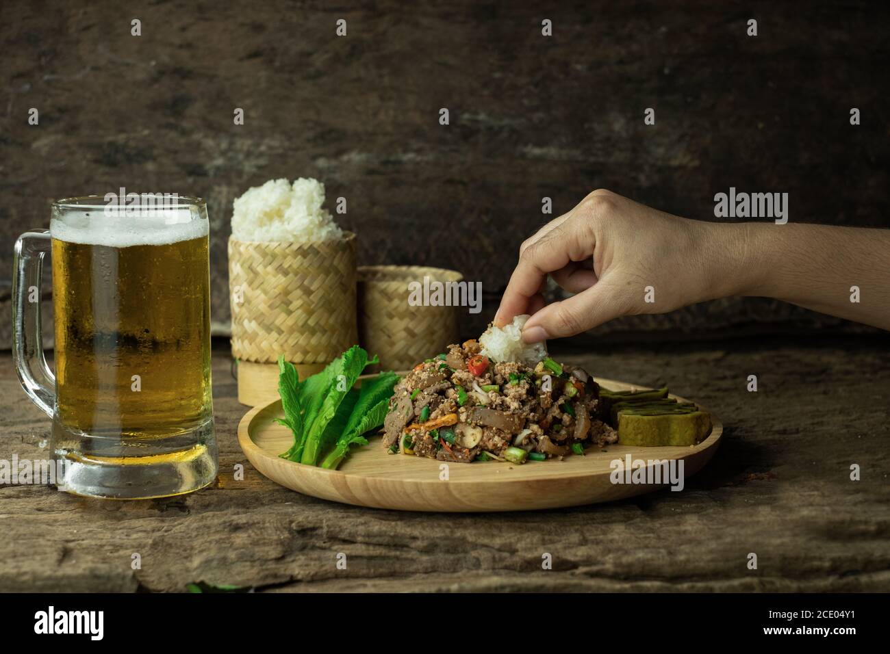 Using a hand to eat sticky rice and spicy minced pork salad with beer ...