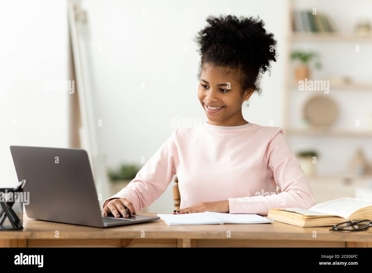 African American Girl Doing Homework On Laptop Computer Sitting Indoors ...