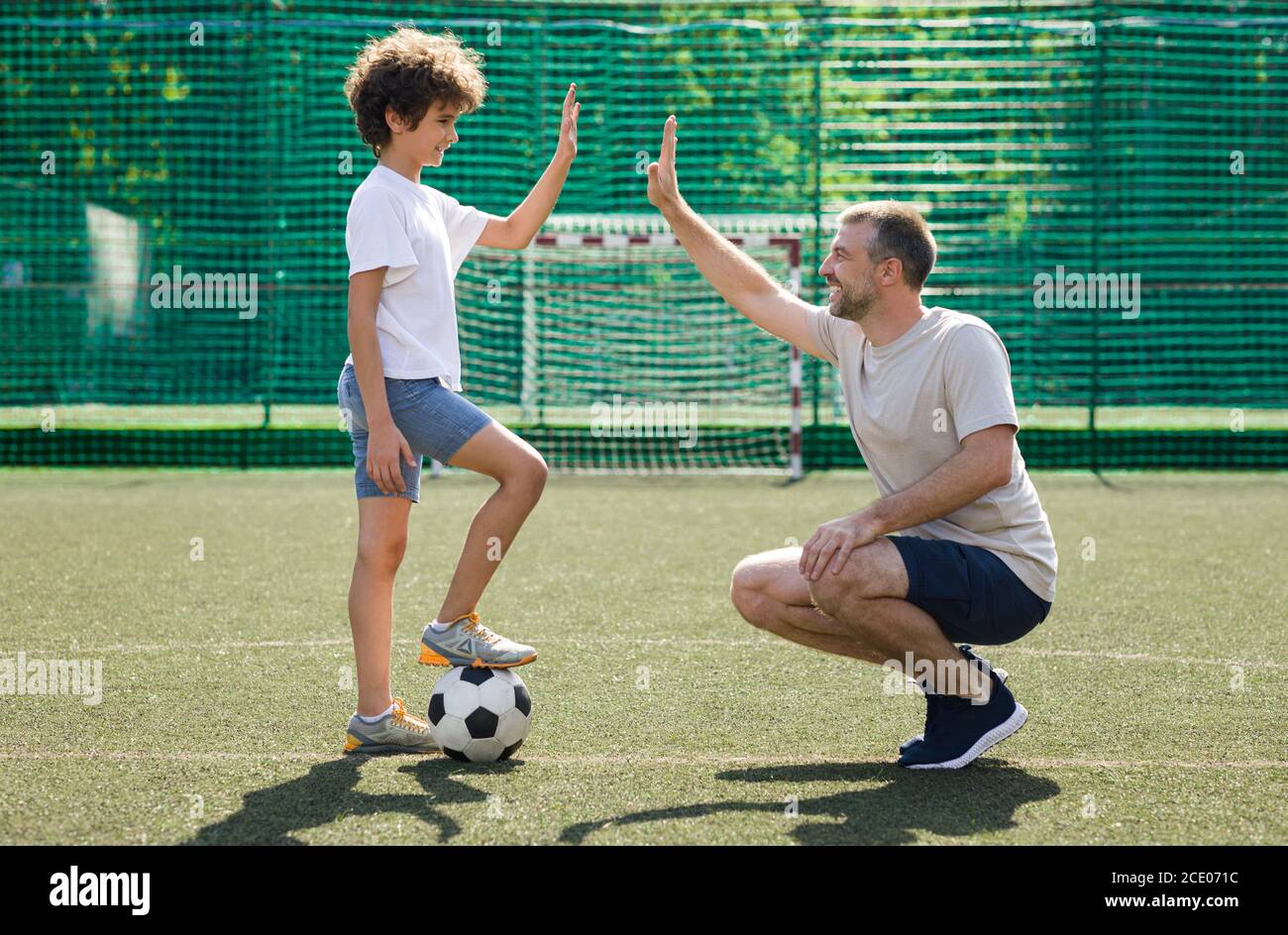 Happy father playing football on a field with son Stock Photo - Alamy