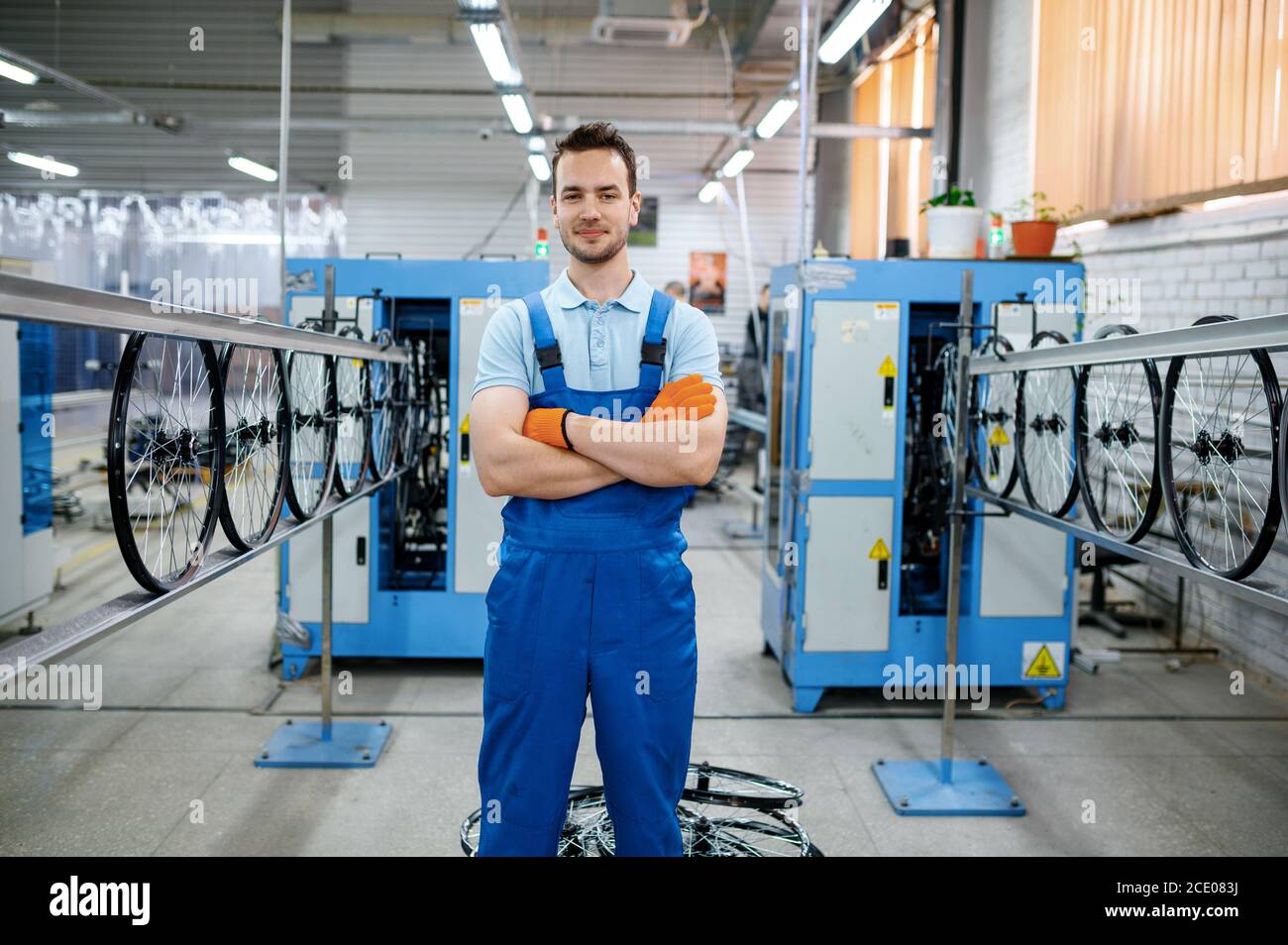 Worker in uniform poses on bicycle wheel factory Stock Photo - Alamy
