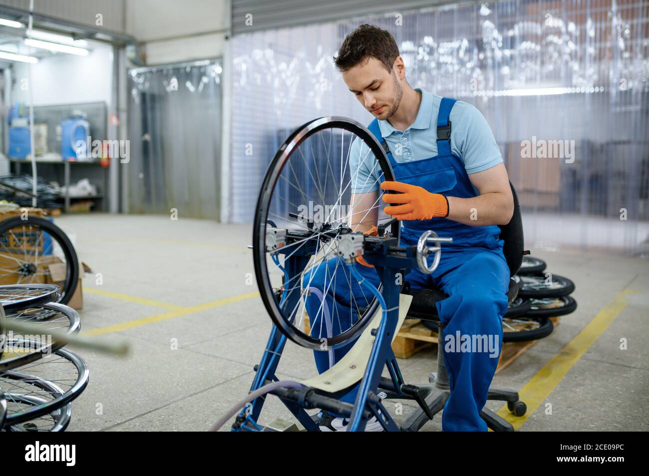 Male worker at the machine tool checks bicycle rim Stock Photo - Alamy