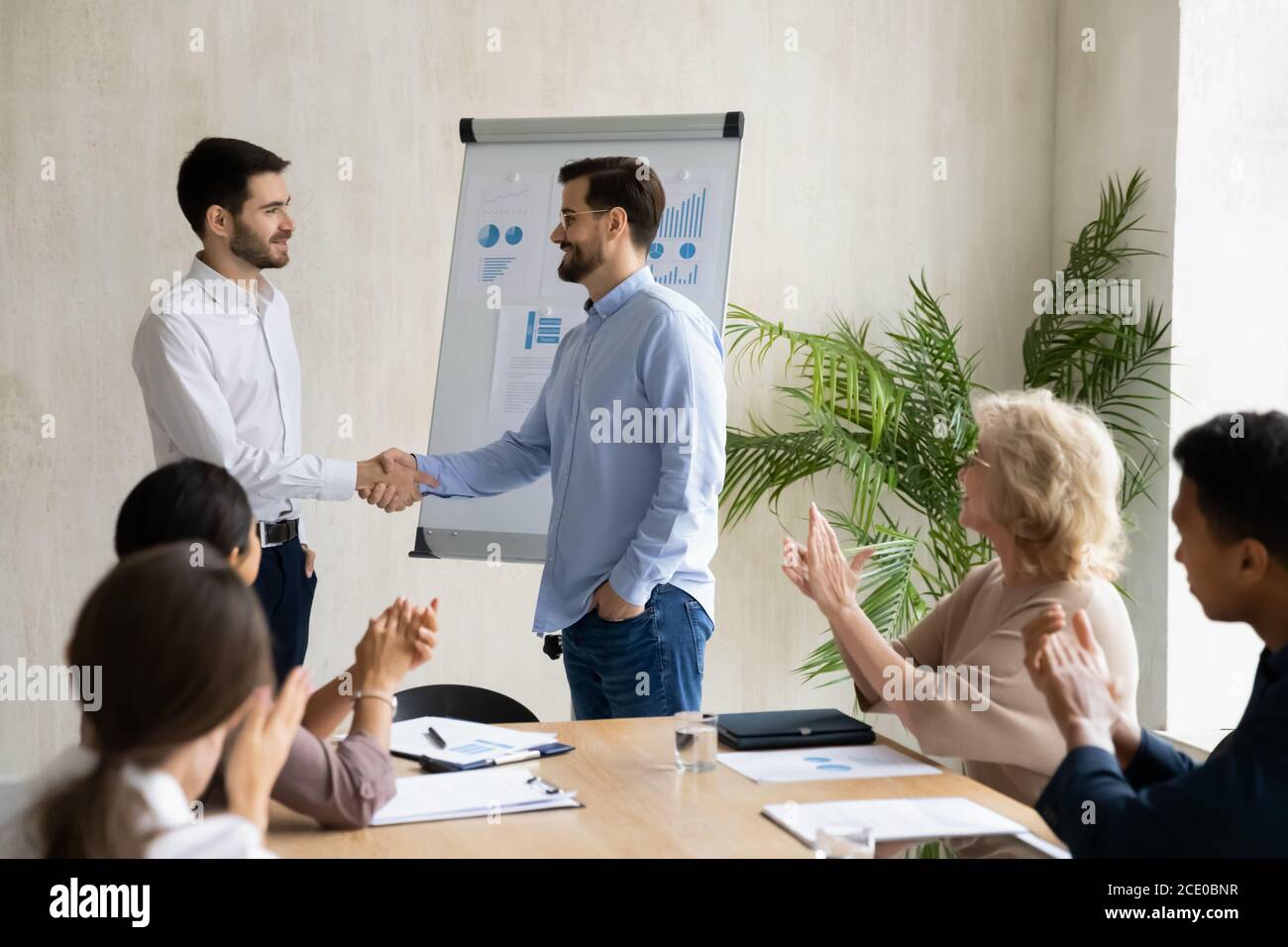 Happy diverse coworkers welcoming newbie in office Stock Photo - Alamy