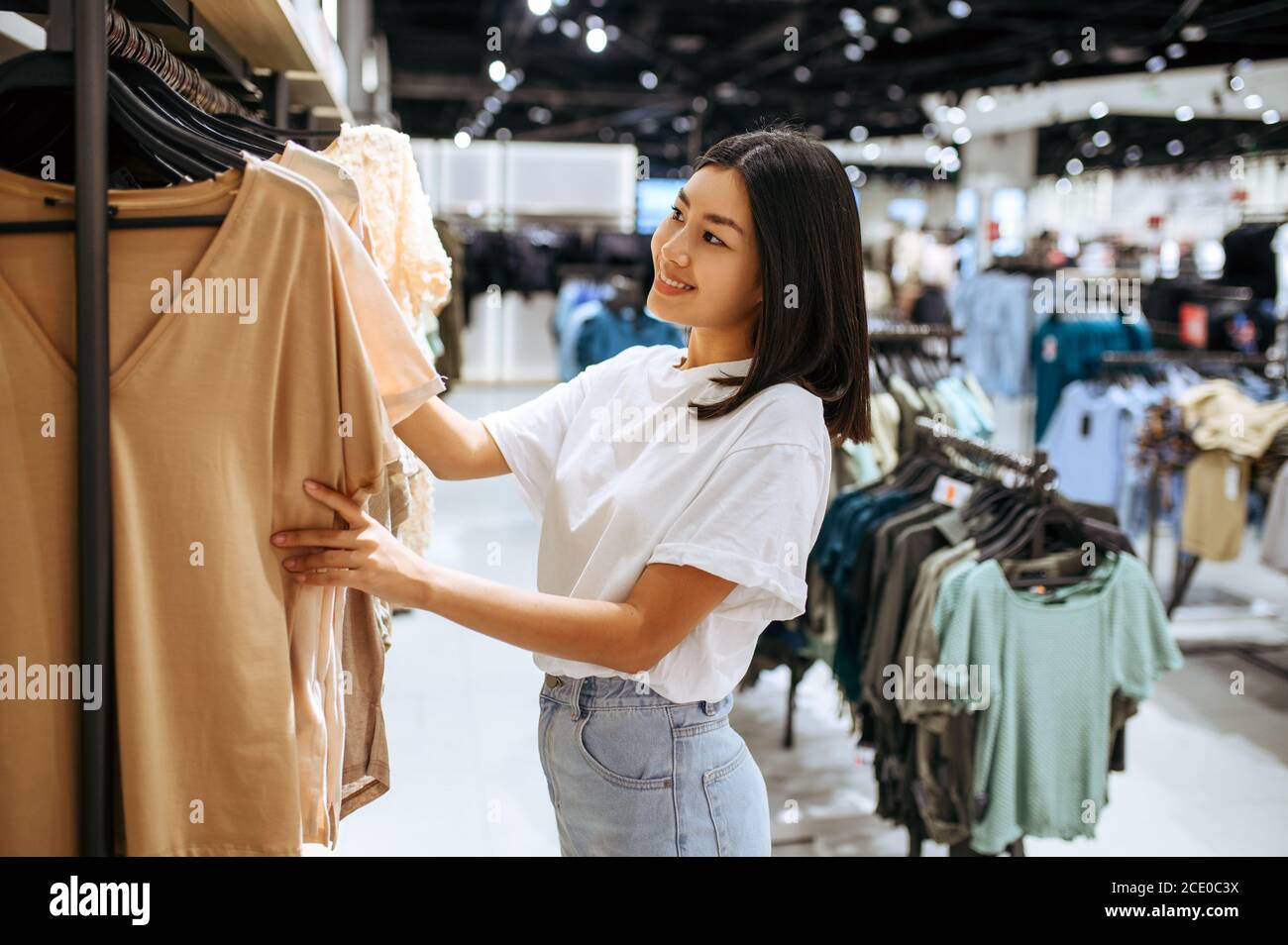 Woman choosing clothes in clothing store Stock Photo - Alamy