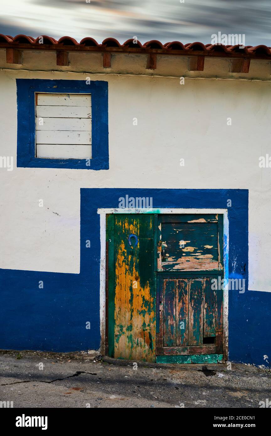 White fronted poor house with a badly worn wooden door with a horseshoe ...