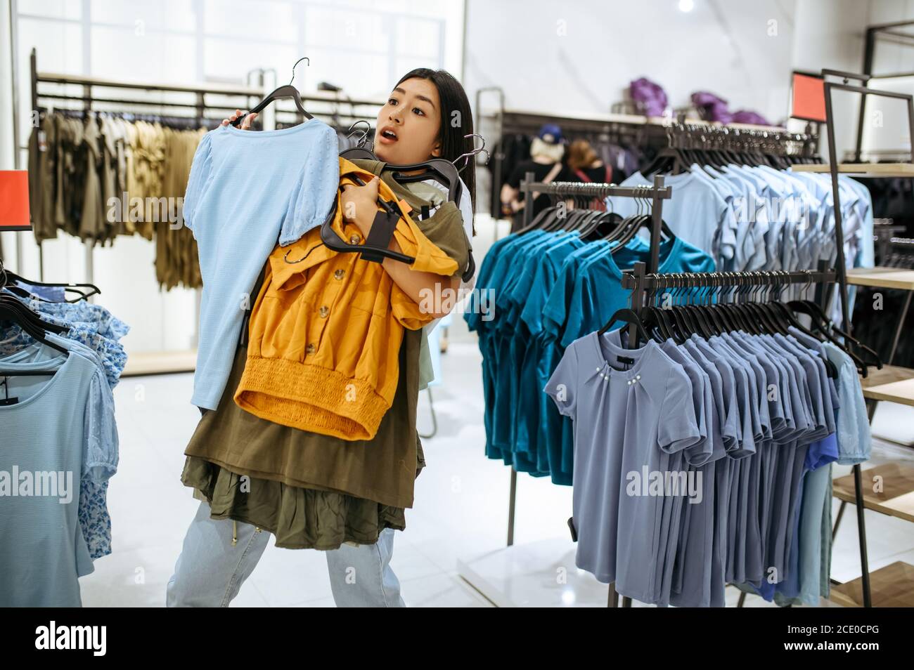 Customer holds clothes on hanger in clothing store Stock Photo - Alamy