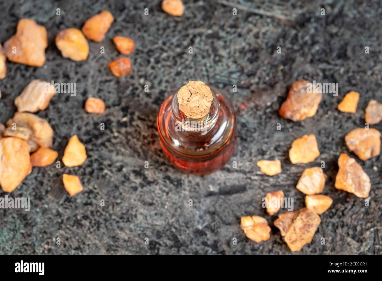 A bottle of styrax benzoin essential oil and resin on a dark background ...