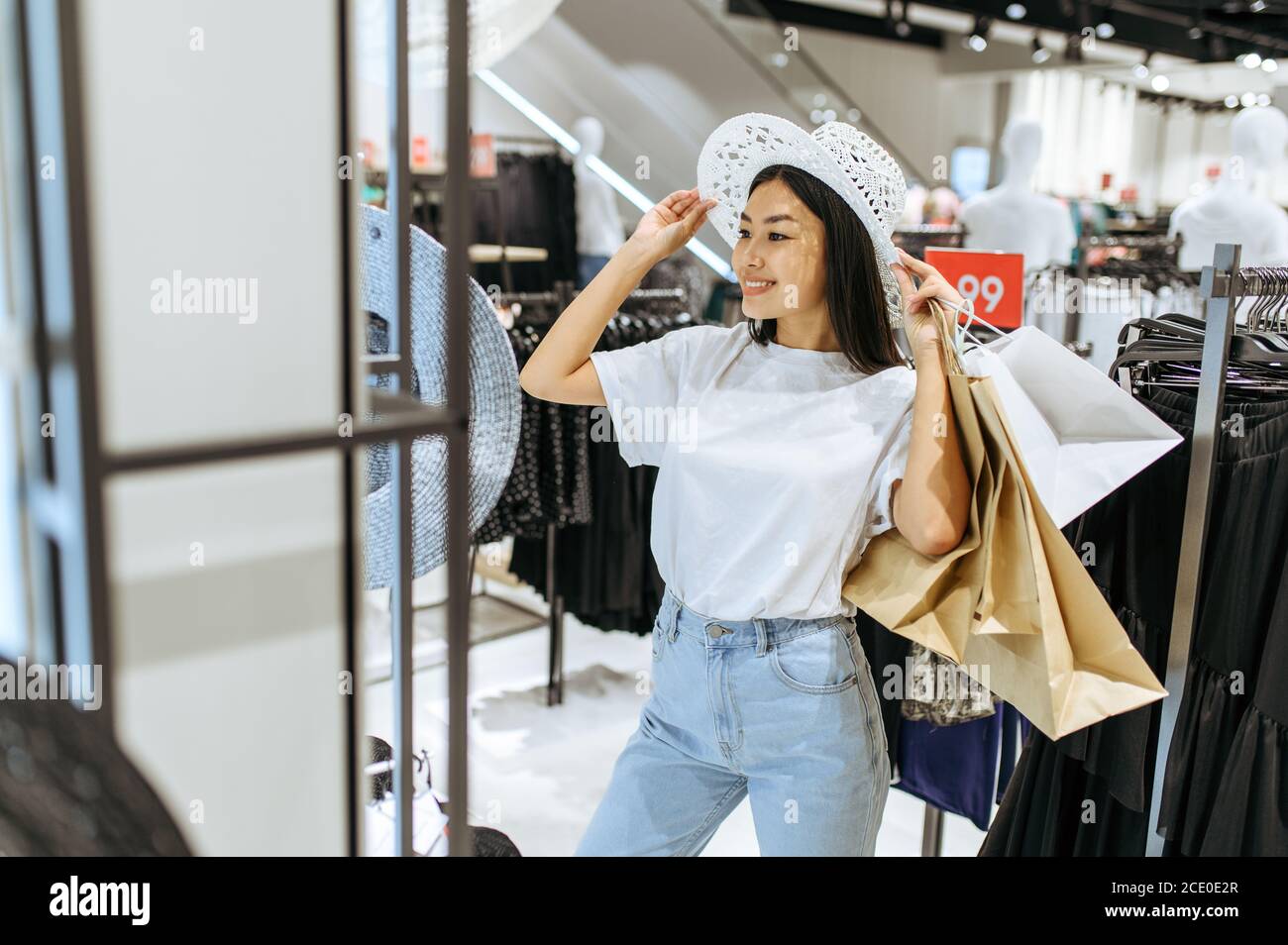 Smiling woman choosing hat in clothing store Stock Photo - Alamy