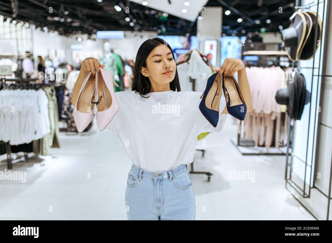 Cute woman choosing shoes in clothing store Stock Photo - Alamy