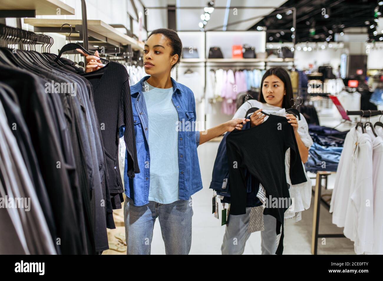 Girls take clothes on hangers in clothing store Stock Photo - Alamy