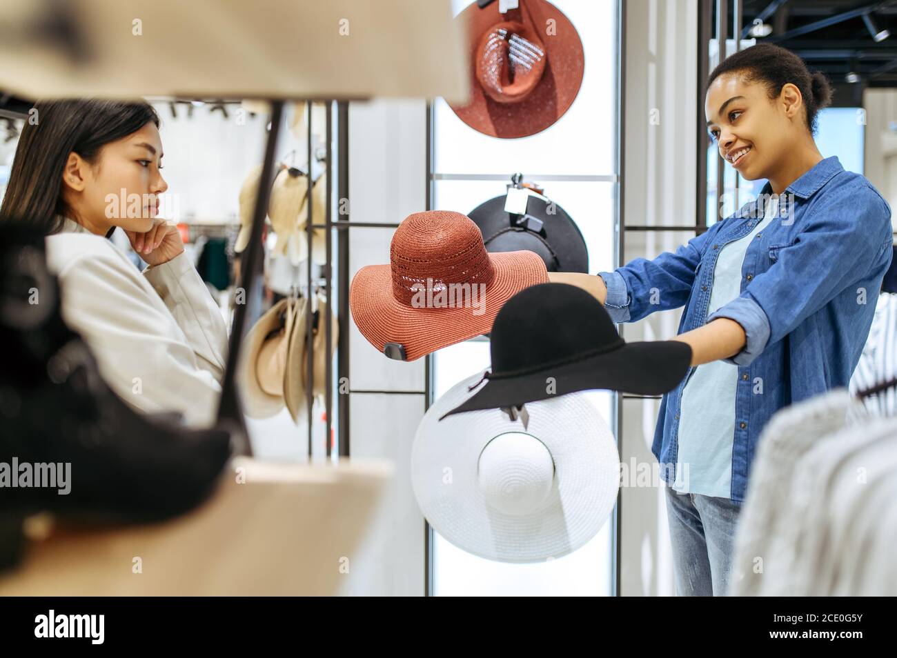 Two girls choosing hats in clothing store Stock Photo - Alamy
