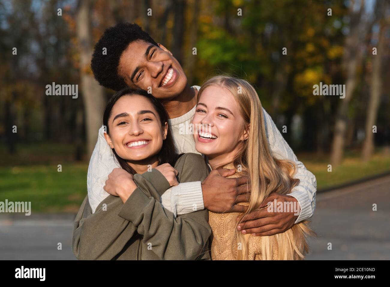 Multiethnic trio of friends smiling over park background Stock Photo ...