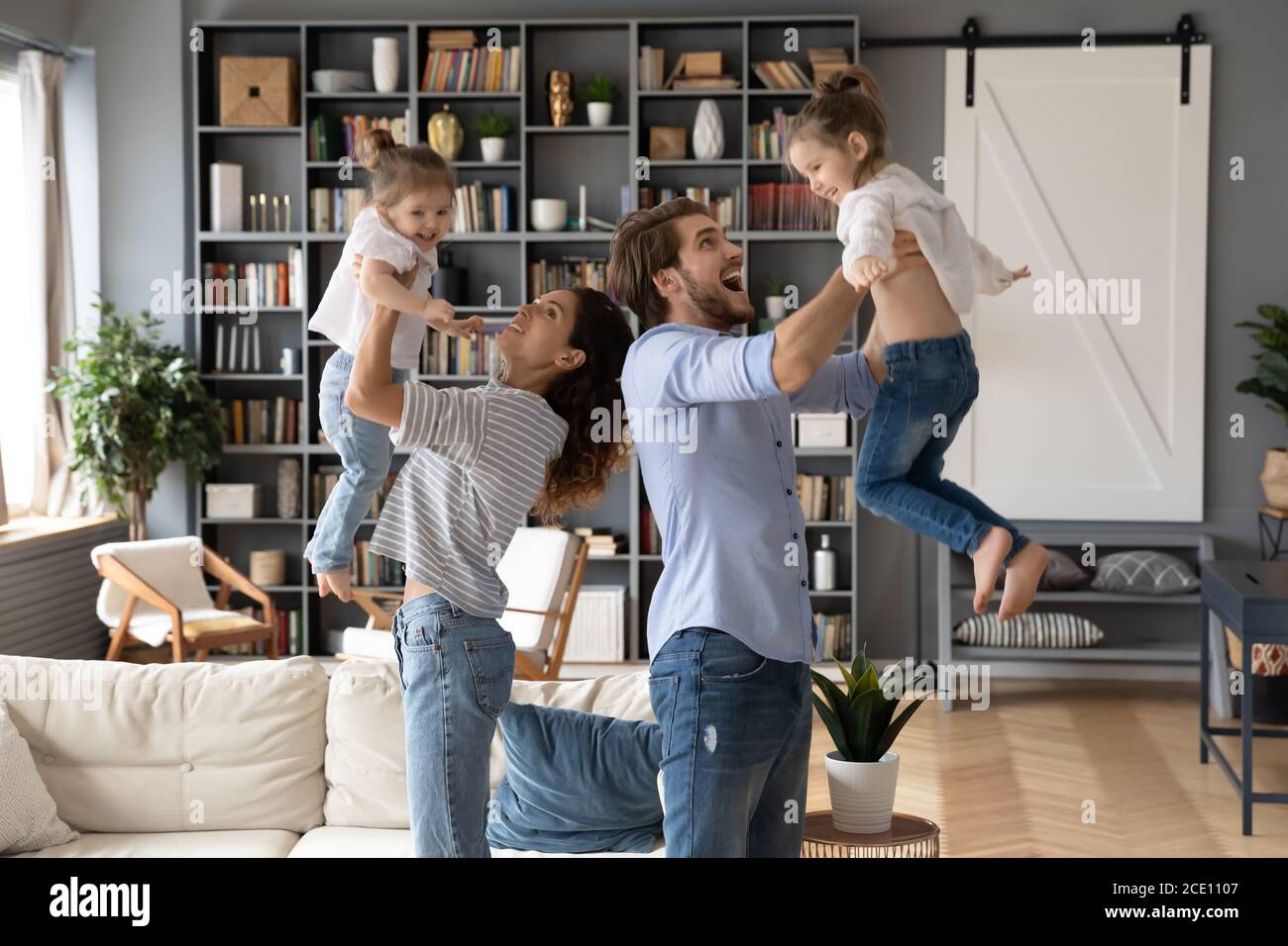 Happy young energetic couple lifting little laughing kids in air Stock ...