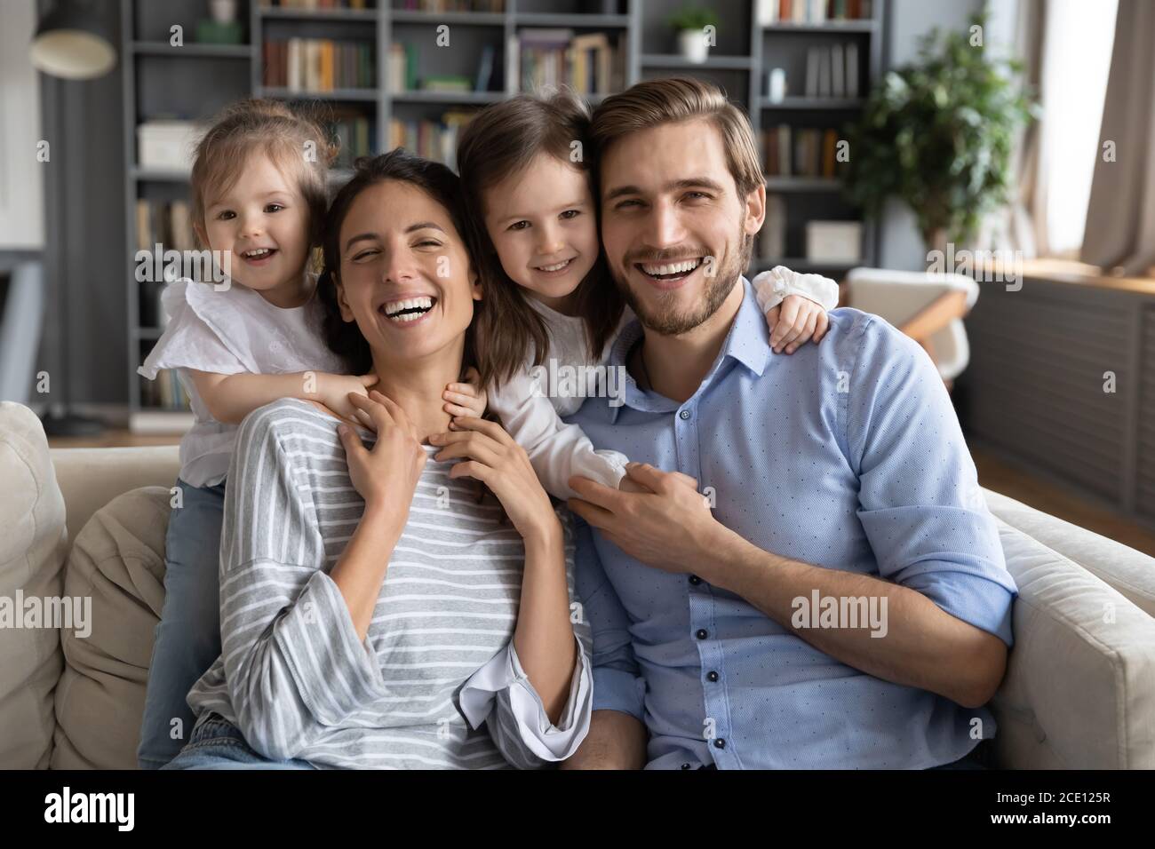 Portrait of affectionate little children cuddling happy young parents ...