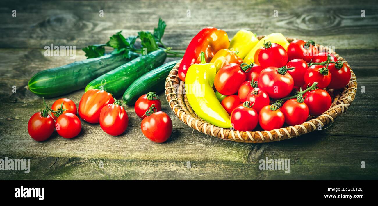 Harvest of fresh ripe vegetables on wooden table and in rod bowl ...