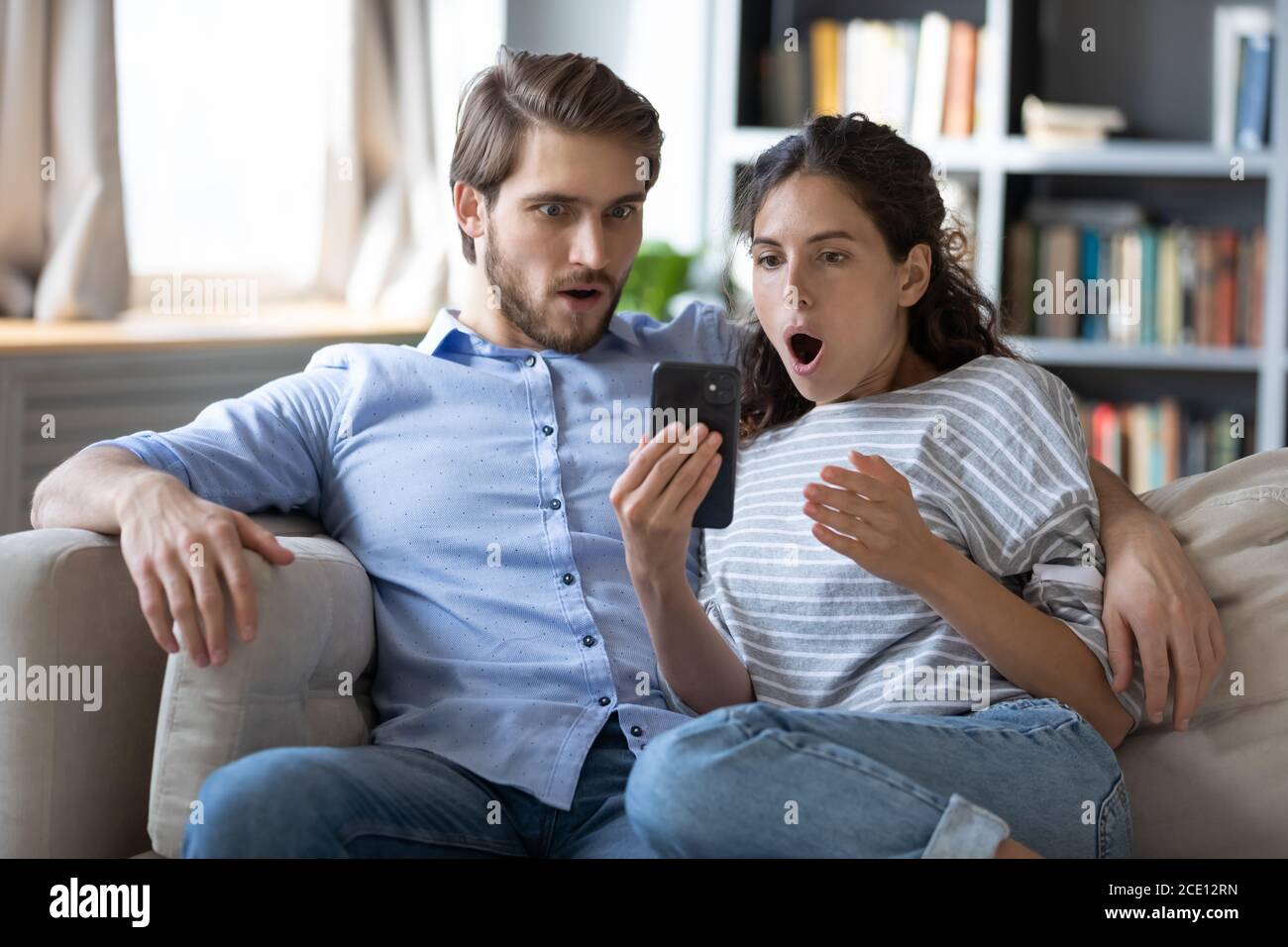 Shocked family couple looking at mobile screen with open mouths Stock ...