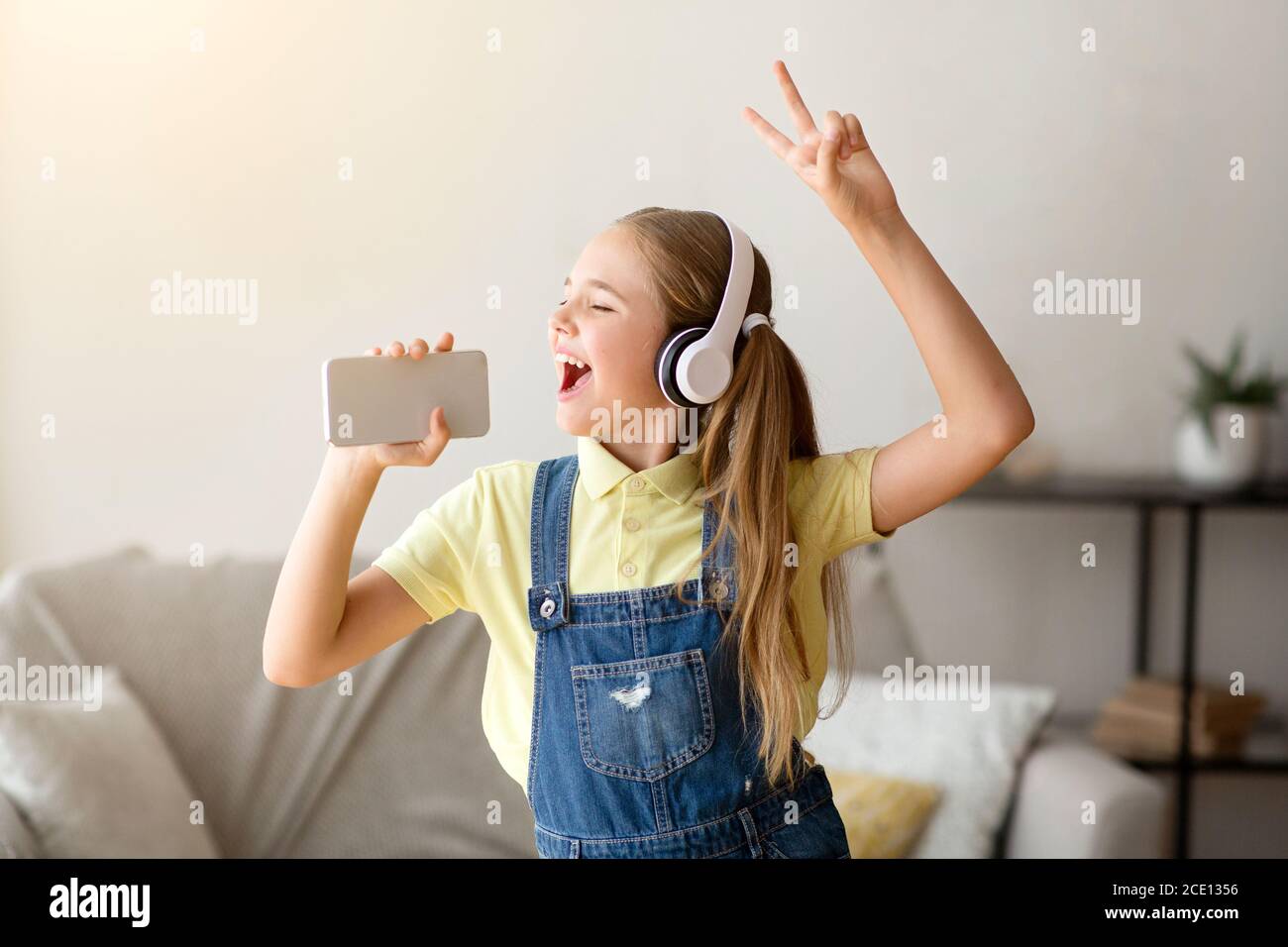 Teenage girl singing using smartphone as mic Stock Photo - Alamy