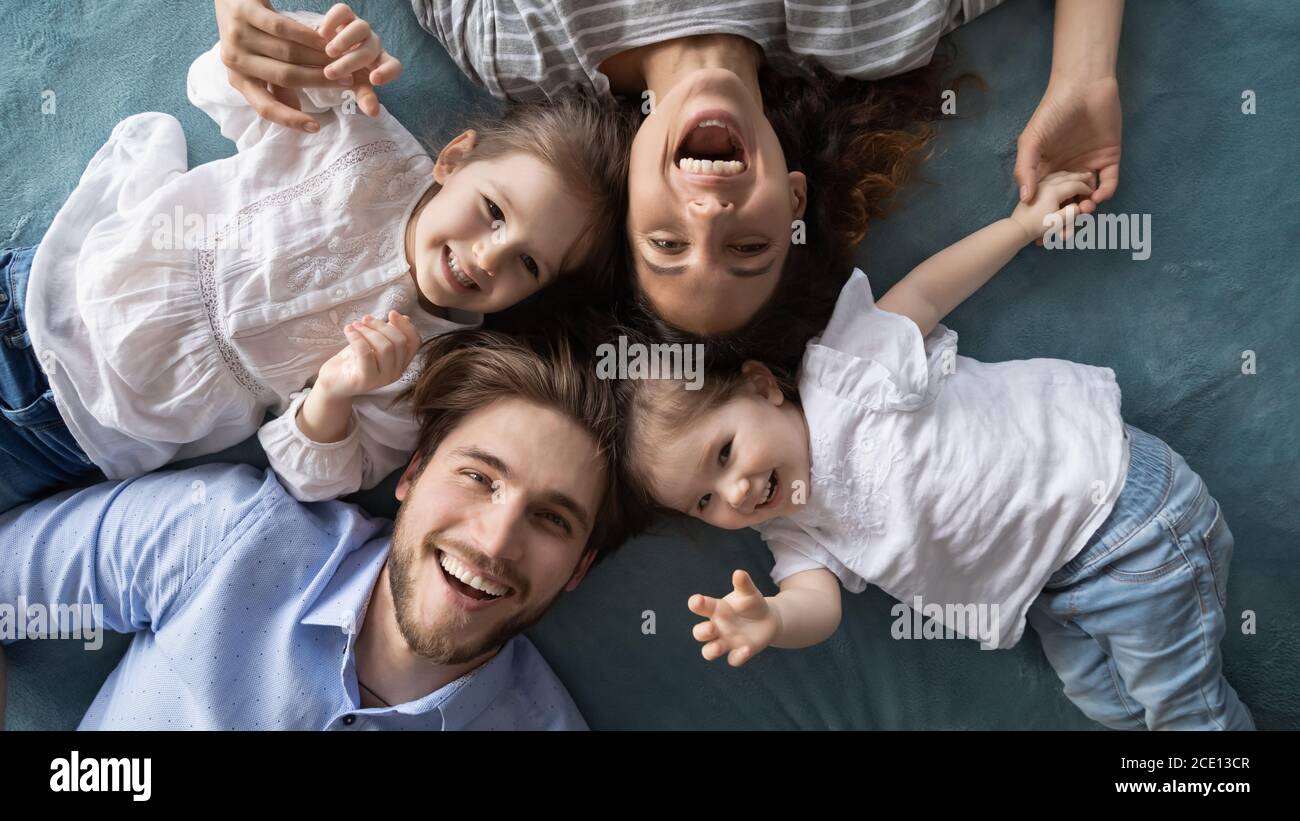 Happy young parents relaxing on bed with joyful little daughters Stock ...