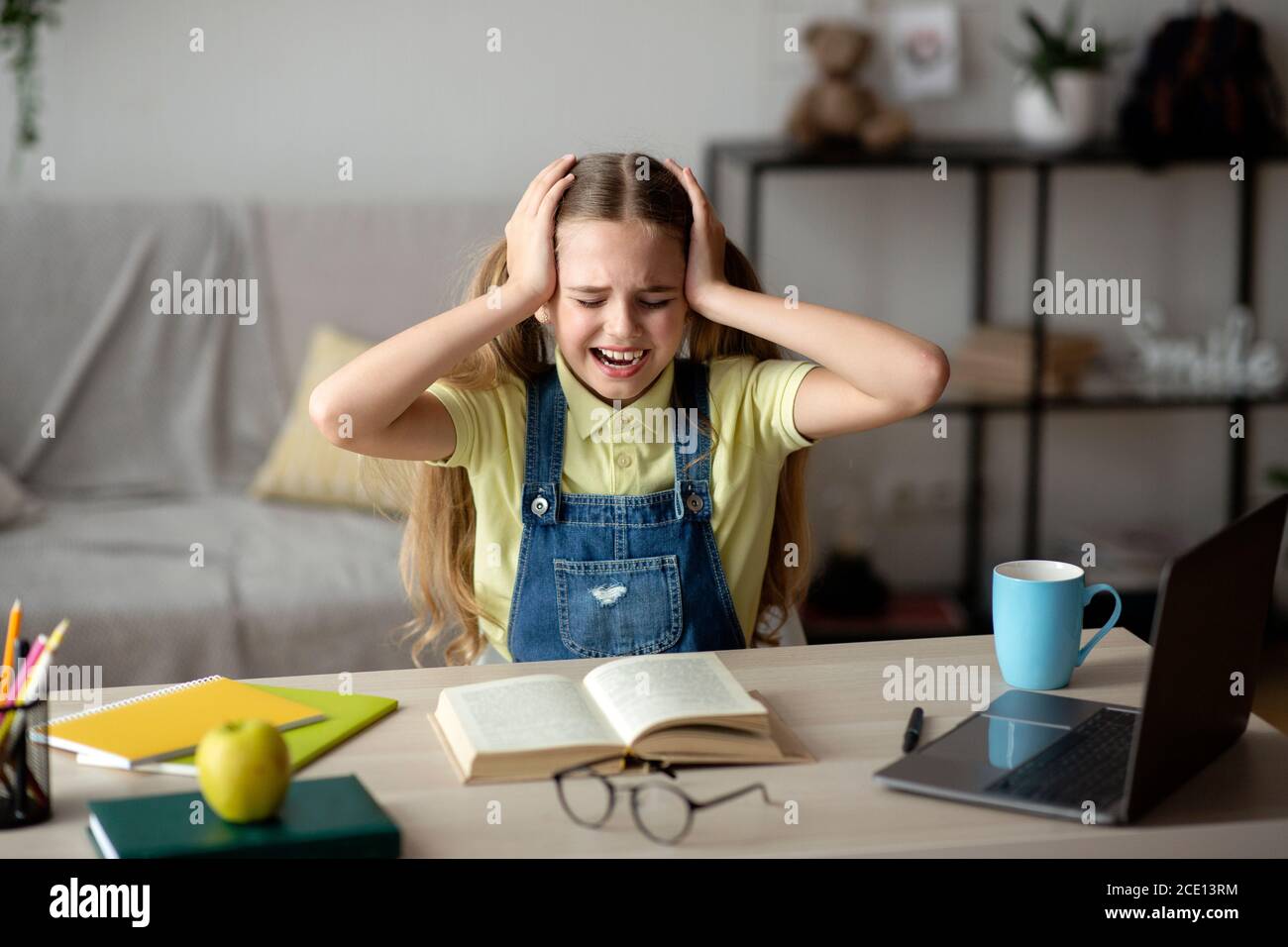 Tired school girl screaming while reading book Stock Photo - Alamy