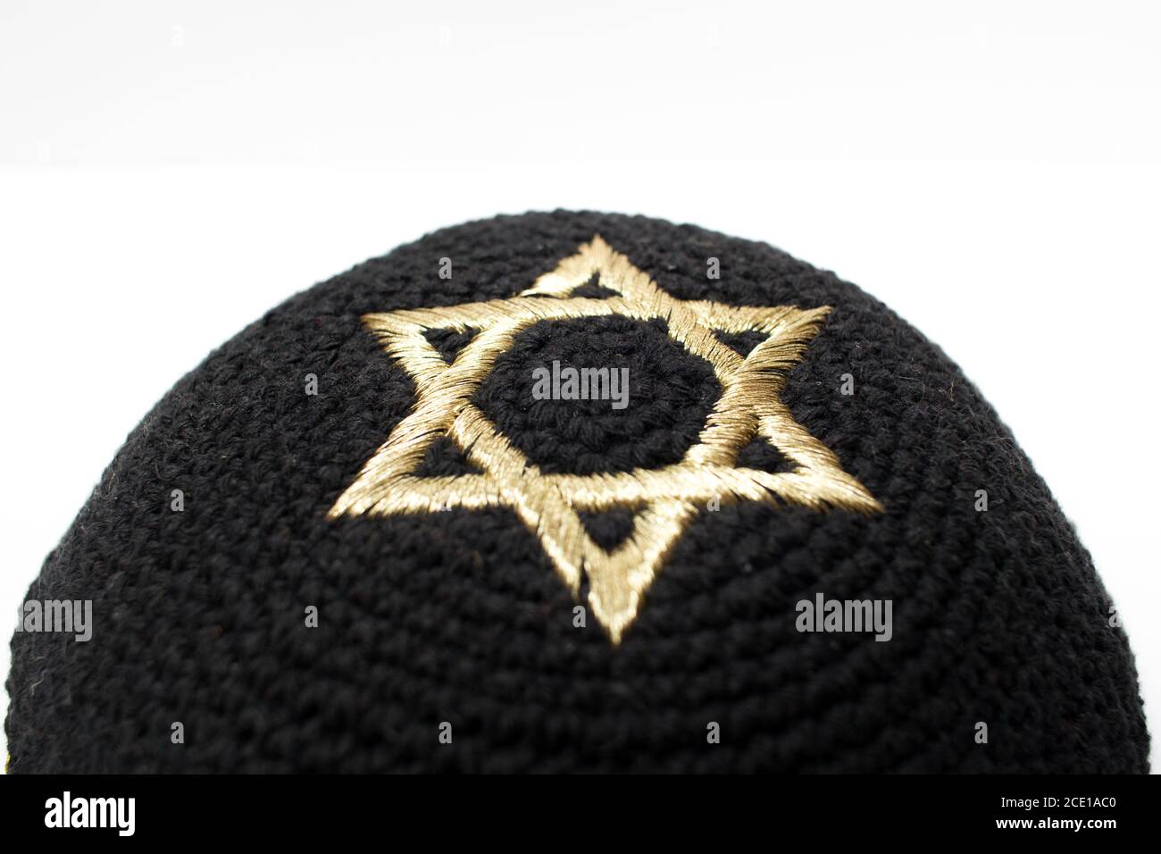 Closeup of a black kippah with a golden david star on top on a white ...