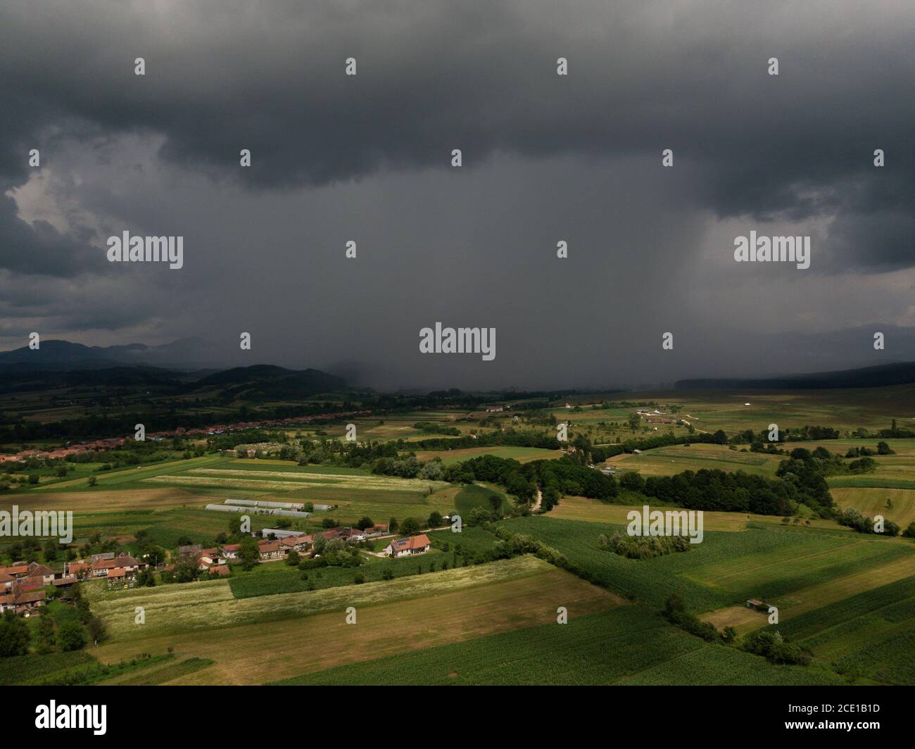 A summer rain storm in the distance, seen over rural agricultural land ...