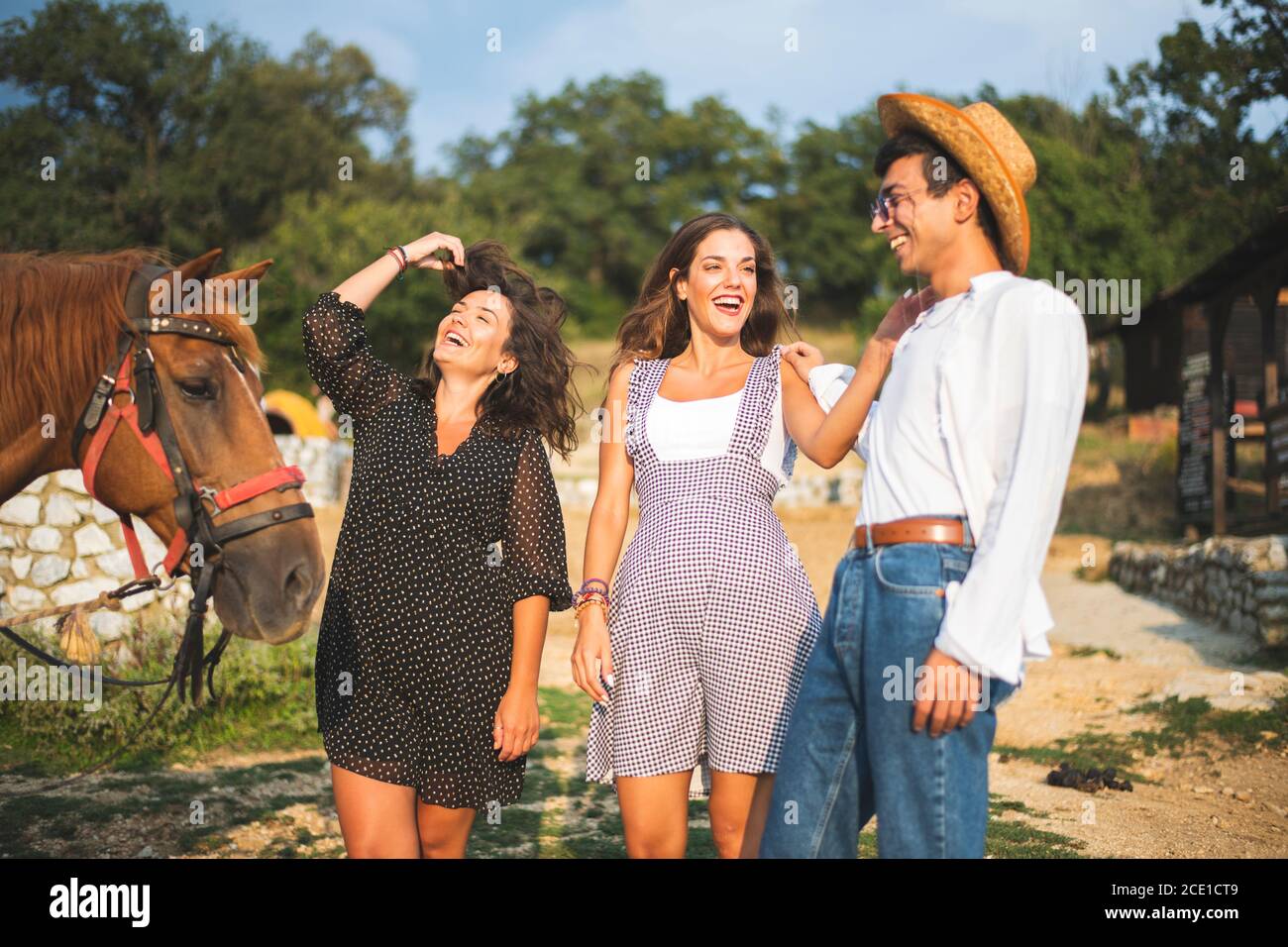 Three Friends Laughing and Having Fun in a Ranch with a Brown Horse ...
