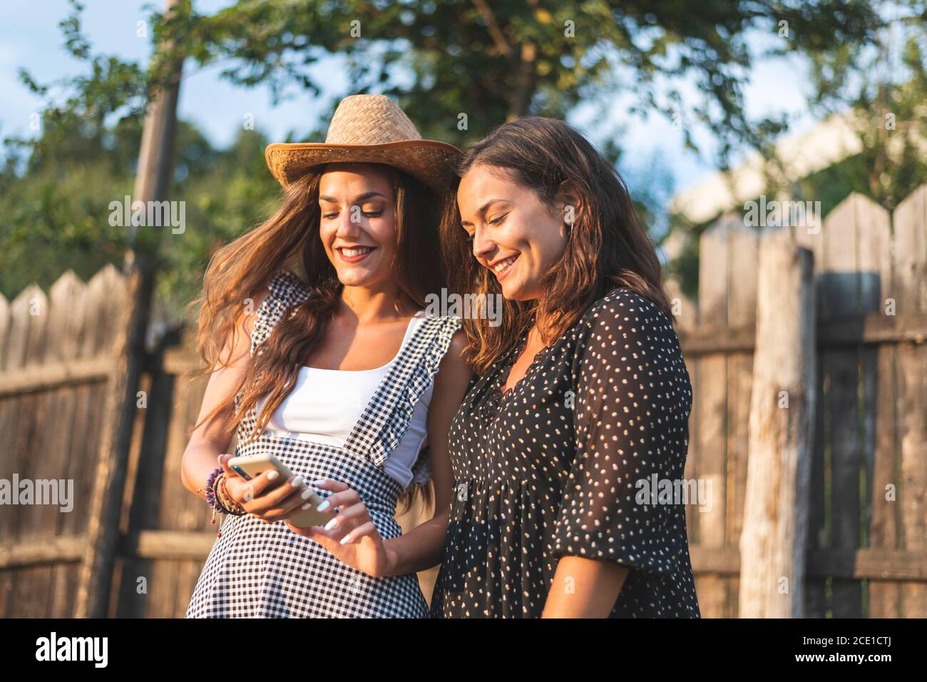 Two Beautiful Girl Friends Using a Smartphone and Smiling. Ranch ...