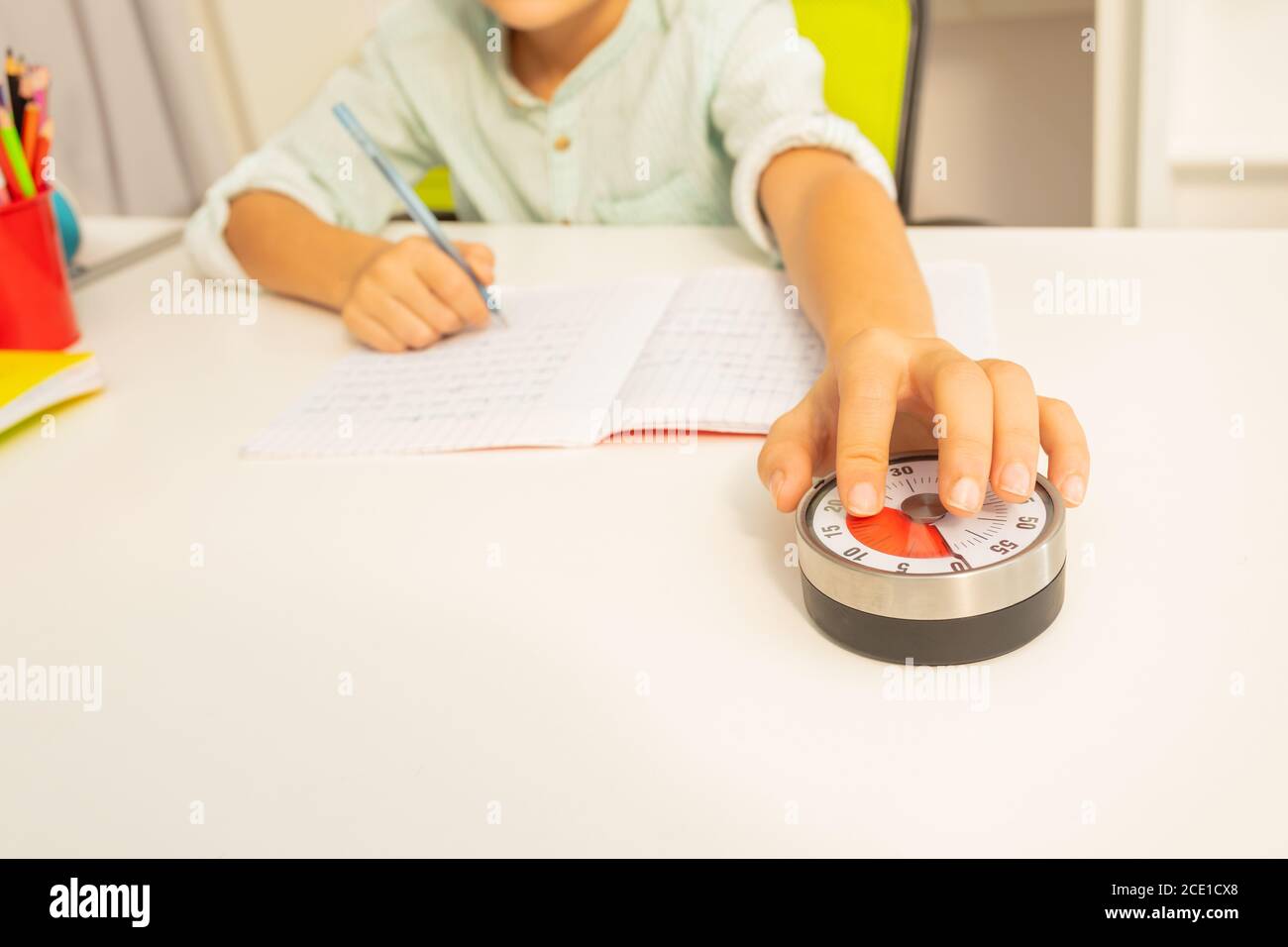 Little autistic boy hold lesson timer with hand while doing writing ...