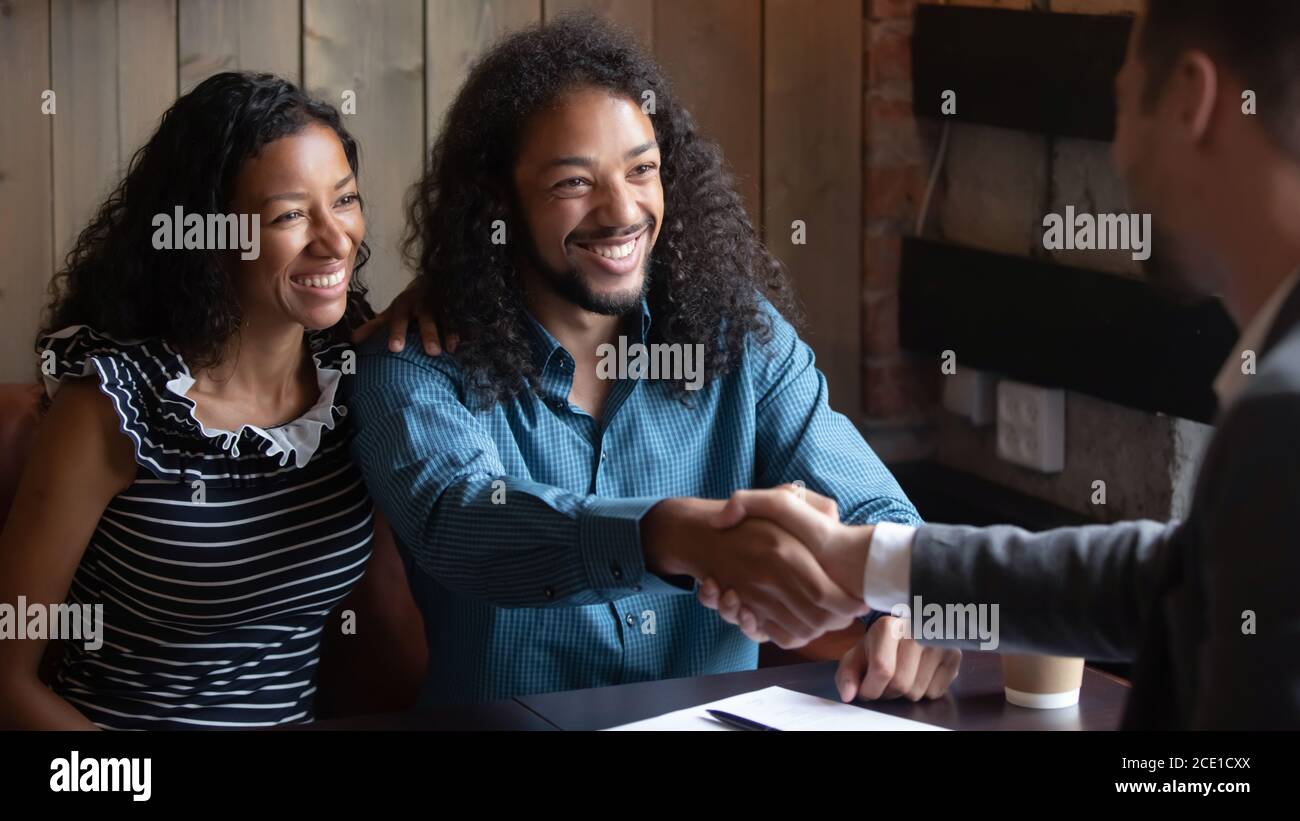 Smiling African American man shaking realtor hand, family making deal ...
