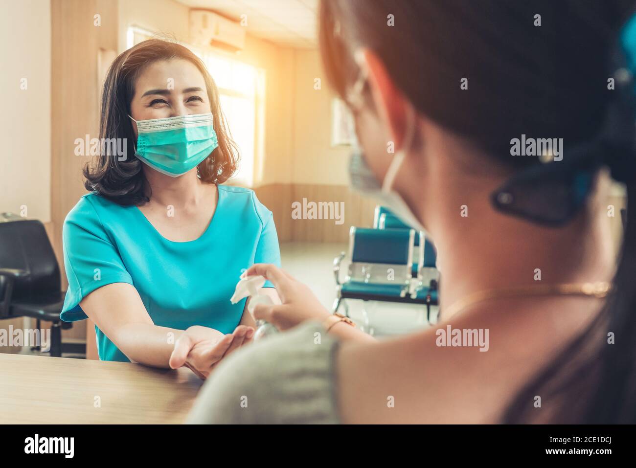 Receptionist and guest wearing face mask at front desk Stock Photo - Alamy