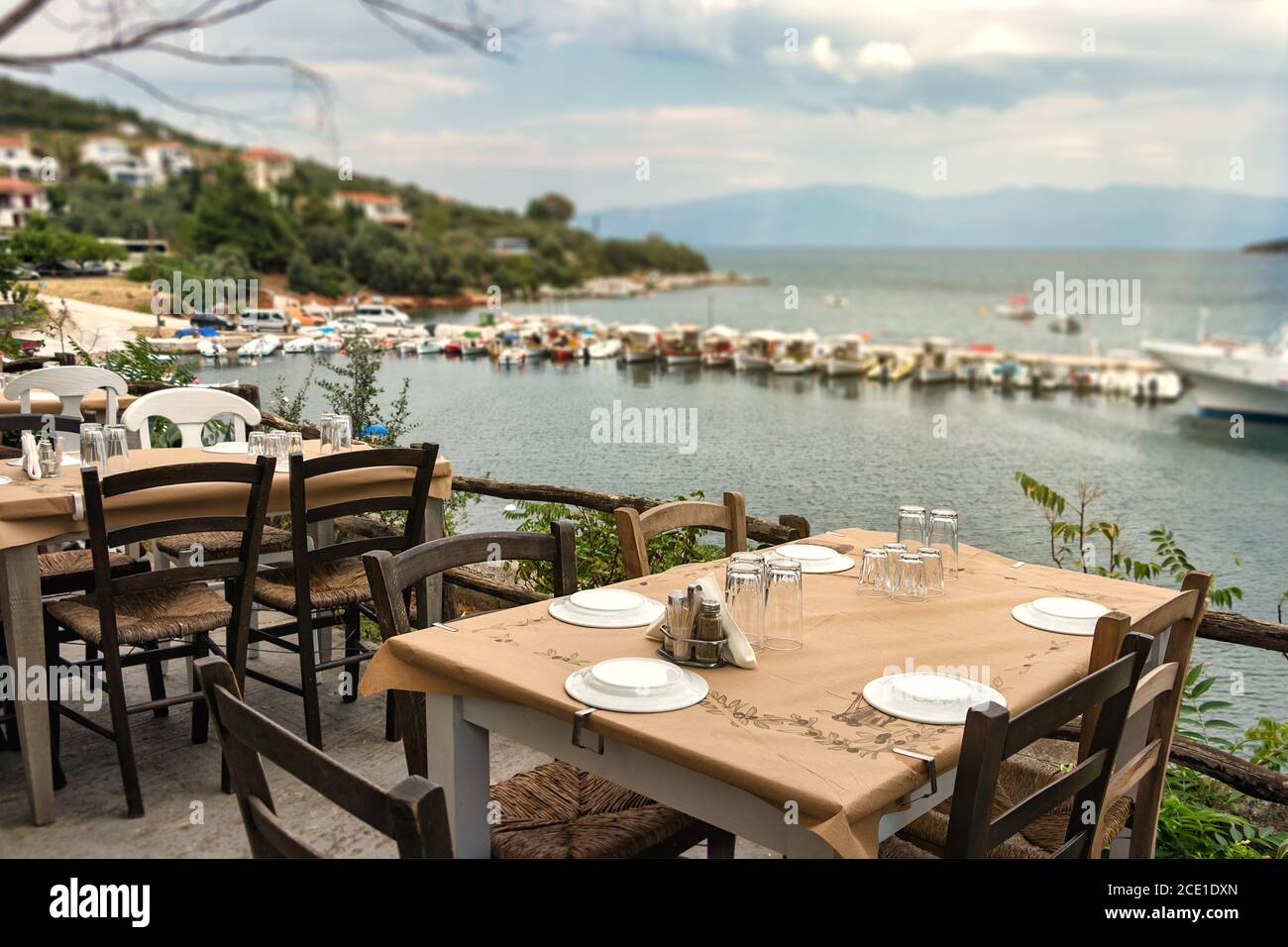 Traditional wooden tables and chairs of a greek tavern over the view of ...