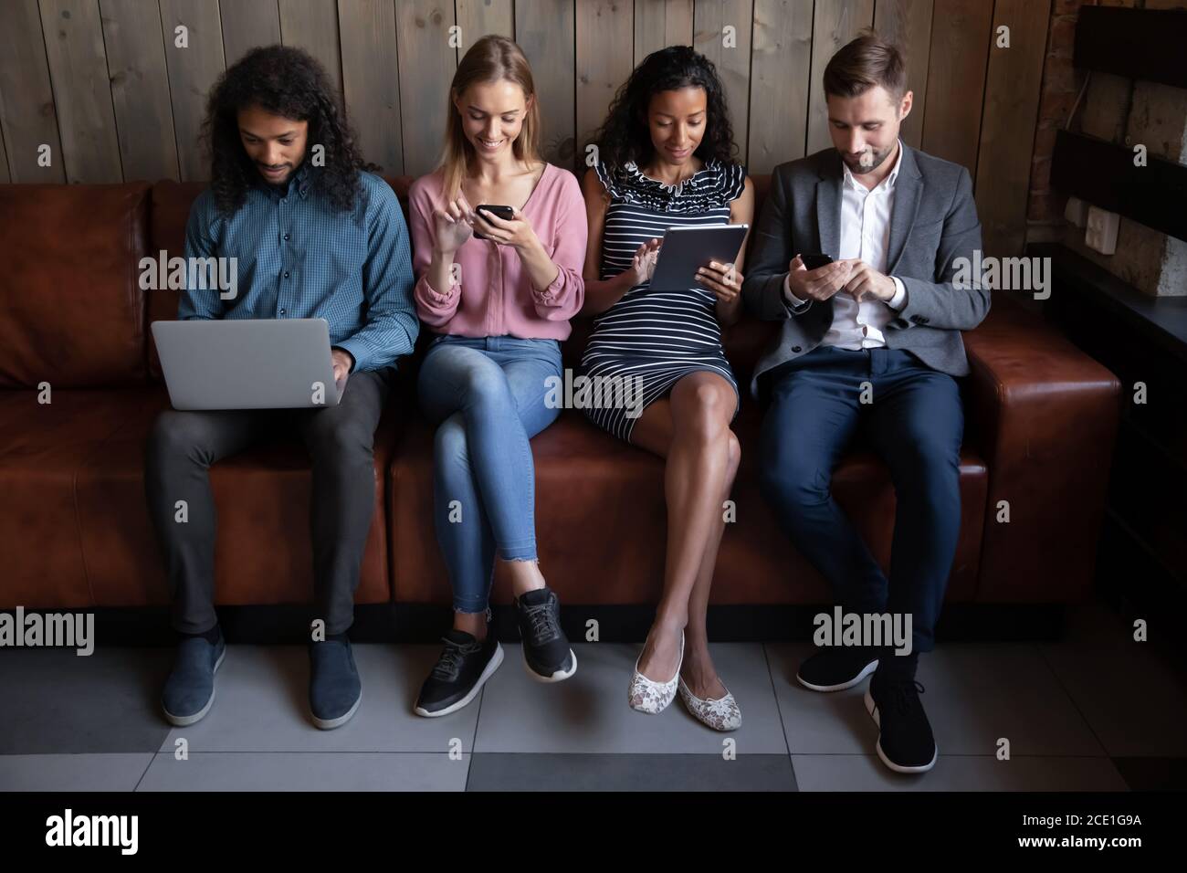 Diverse young people using electronic devices, sitting in row Stock ...