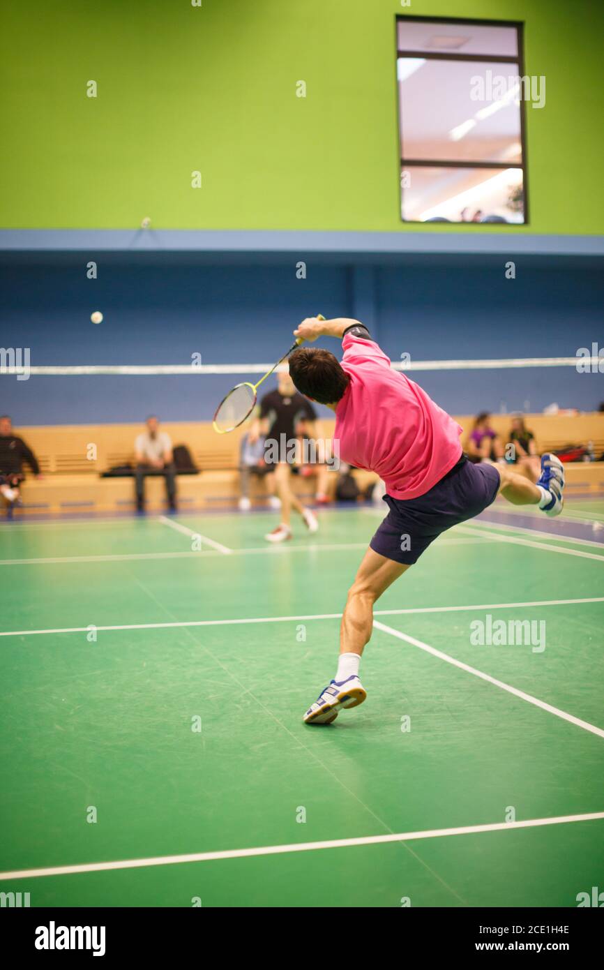 Male badminton player in the middle of a fast paced badminton rally ...