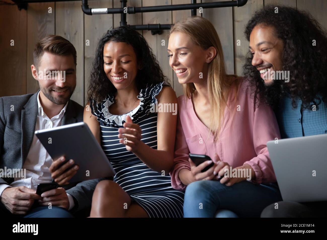 Overjoyed diverse people having fun with gadgets together, chatting ...