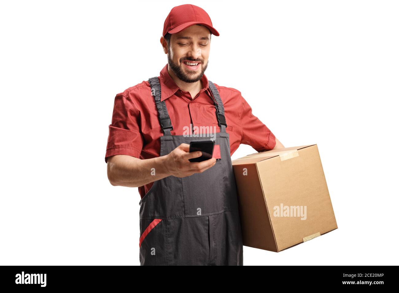 Male worker typing on a mobile phone and holding a cardboard box ...