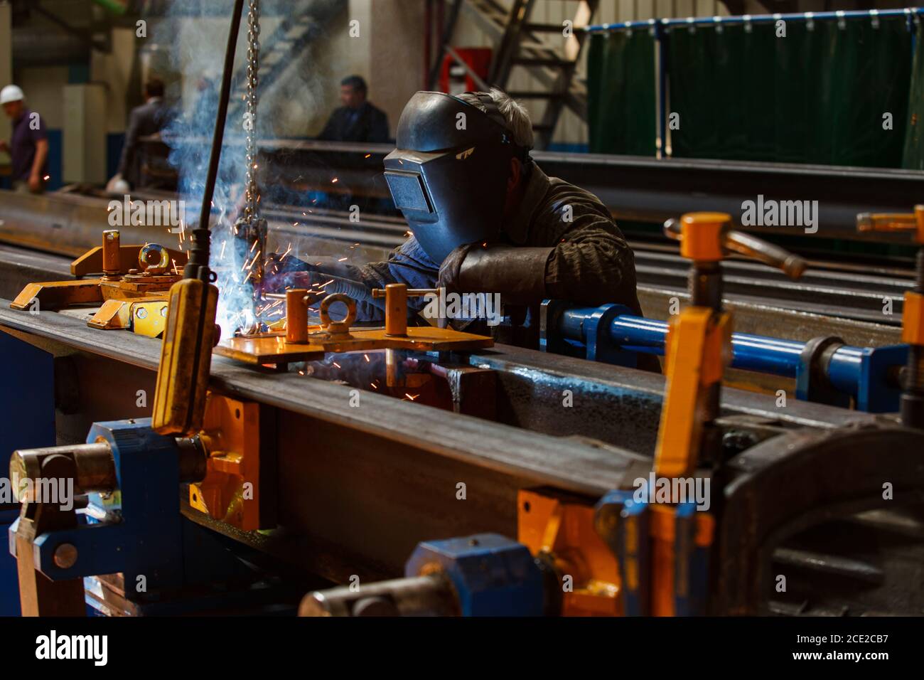 Welder in work. Metal works on machinery production plant. Sparks and ...
