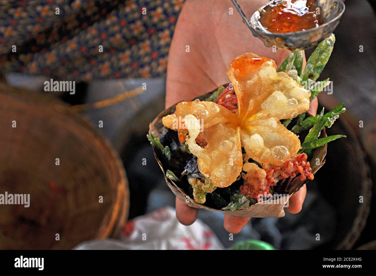 Close up of an open hand holding a cup of fried exotic edible flowers ...