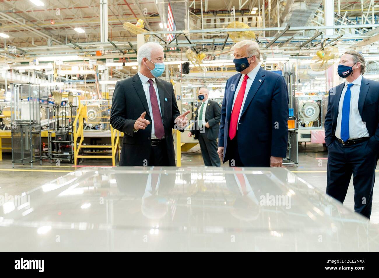 U.S. President Donald Trump, wearing a face mask, is given a tour of a ...
