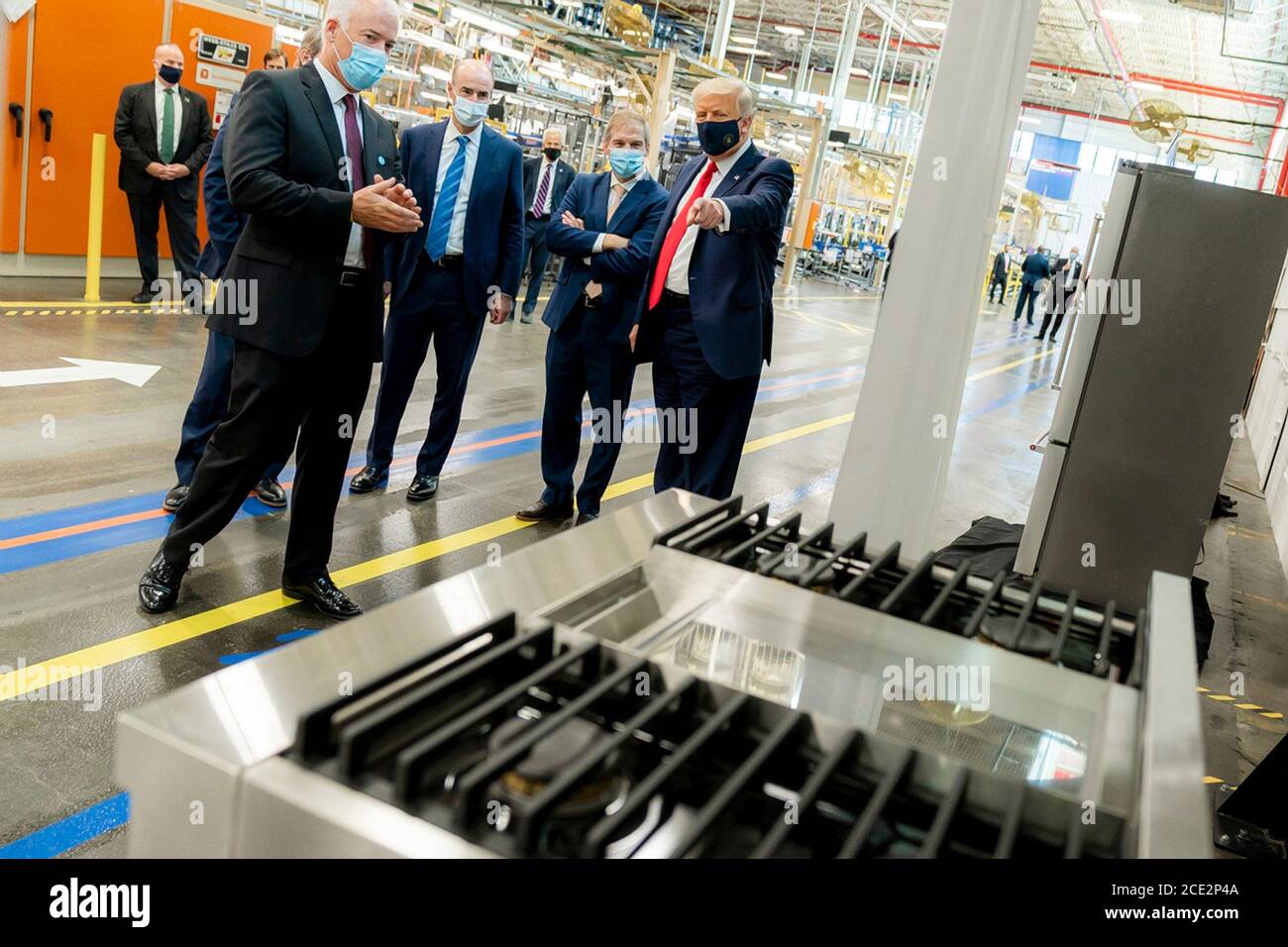 U.S. President Donald Trump, wearing a face mask, is given a tour of a ...