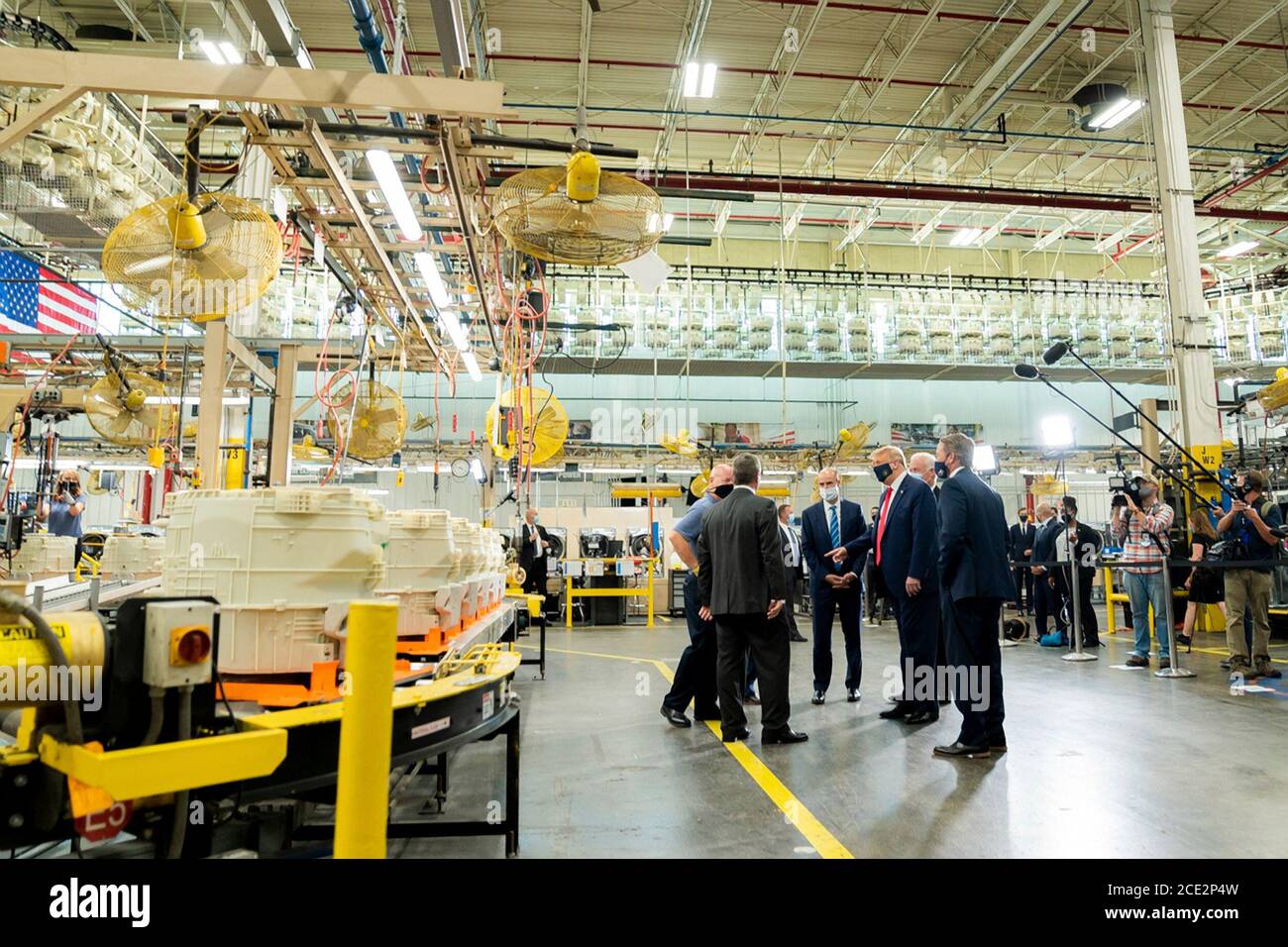U.S. President Donald Trump, wearing a face mask, chats with workers ...