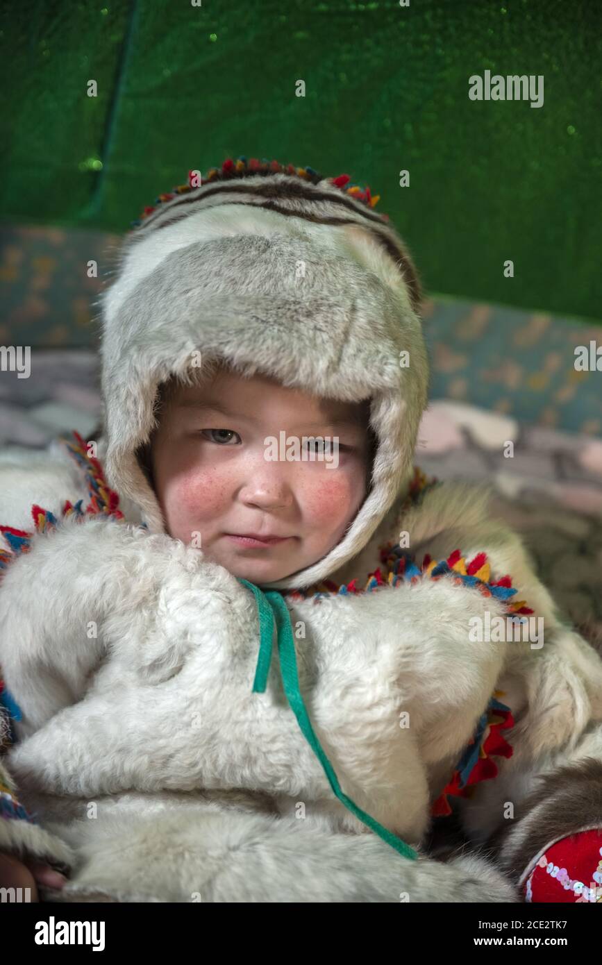 Portrait of a Nenet young girl in traditional wear inside a chum (tent ...