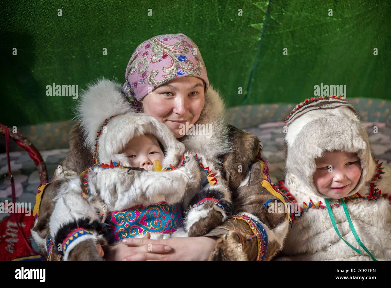 A Nenet mother and her two young daugthers in traditional wear inside a ...