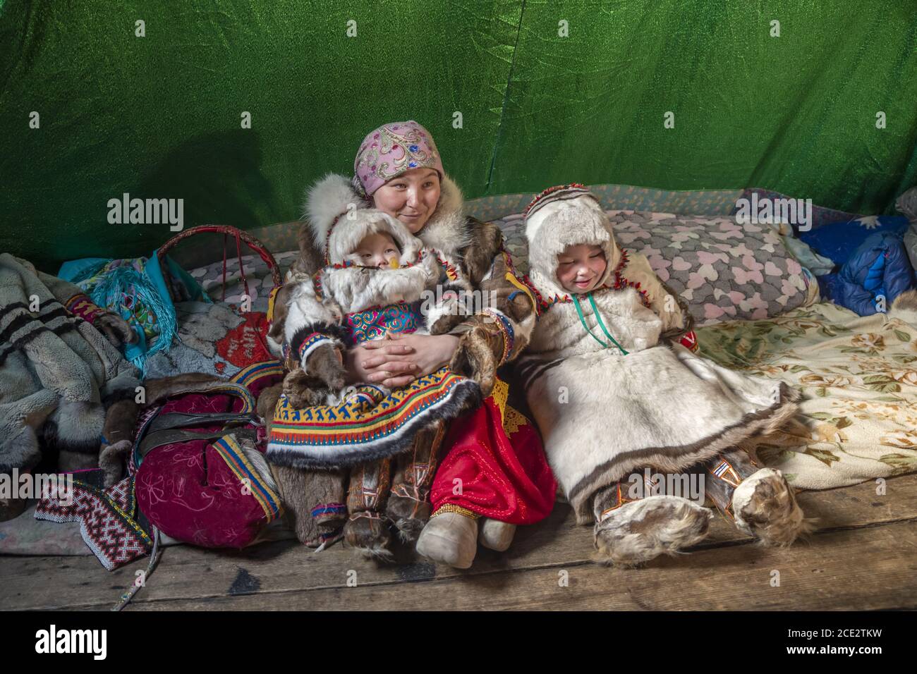 A Nenet mother and her two young daugthers in traditional wear inside a ...