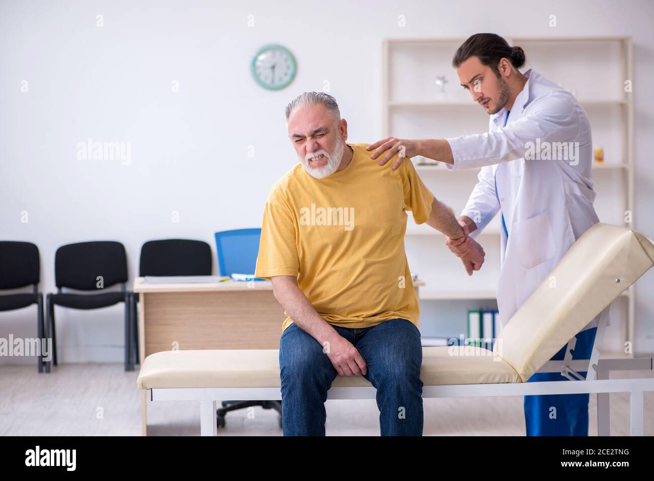 Old injured man visiting young doctor chiropractor Stock Photo - Alamy
