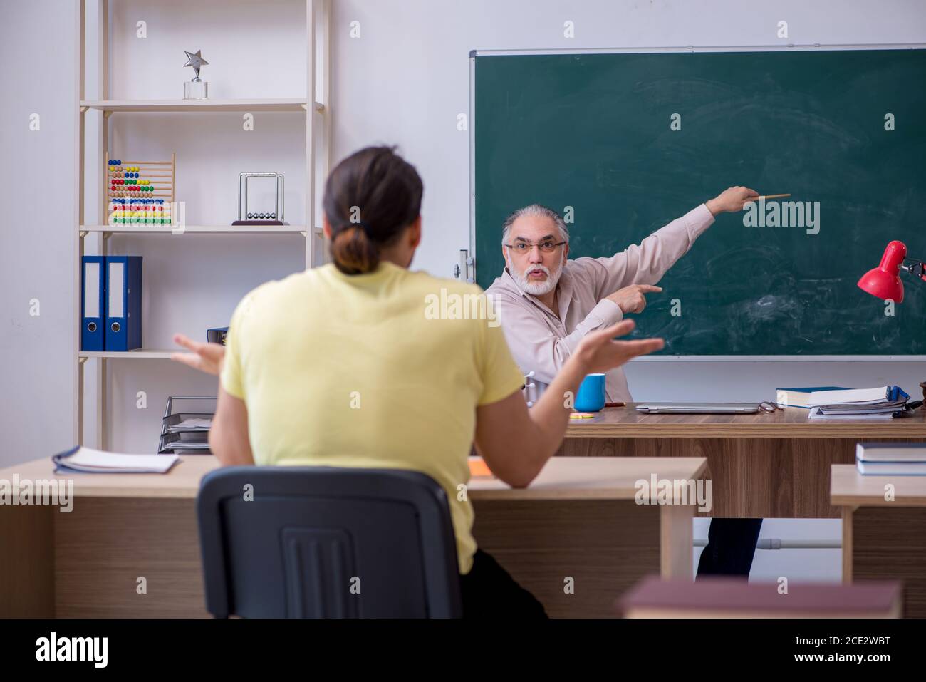 Old teacher and young student in the classroom Stock Photo - Alamy