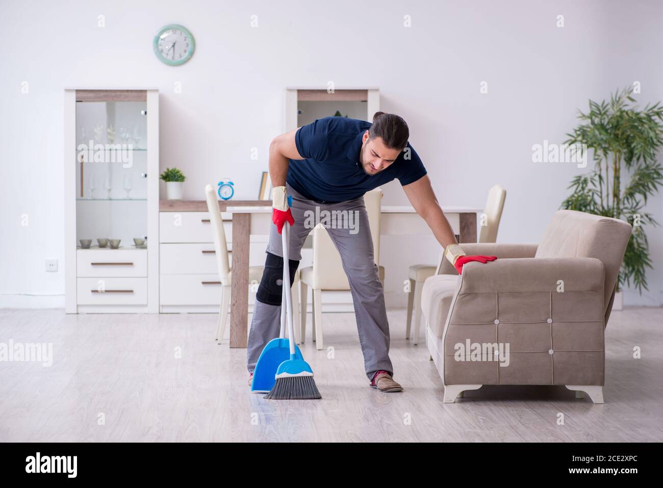 Young leg injured contractor cleaning house Stock Photo - Alamy
