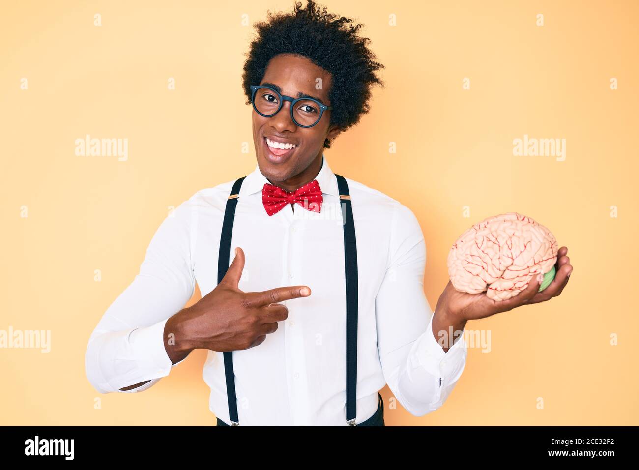 Handsome african american nerd man with afro hair holding brain smiling ...