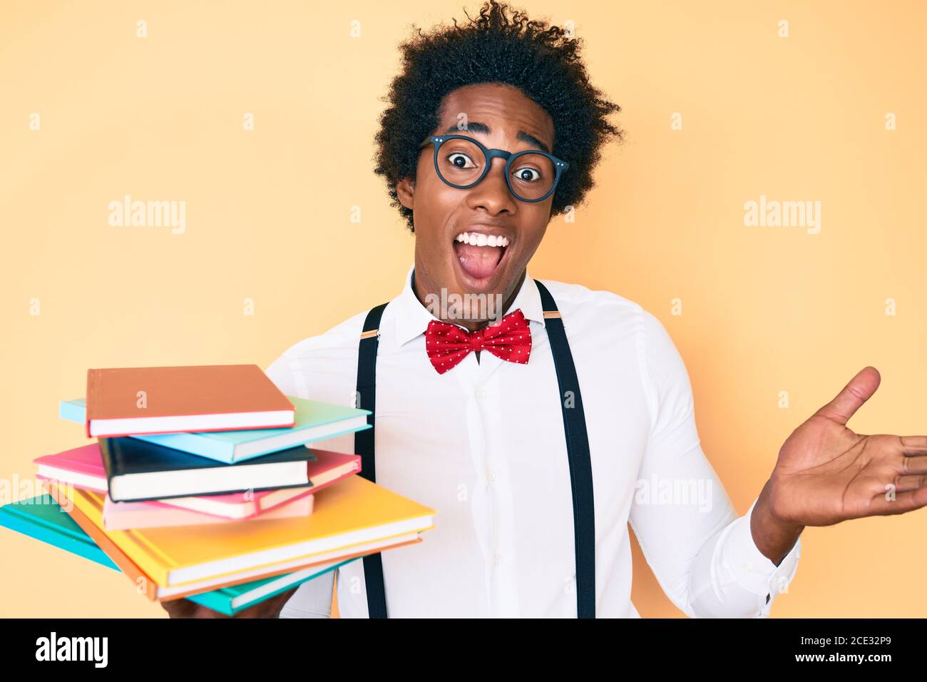 Handsome african american nerd man with afro hair holding books ...
