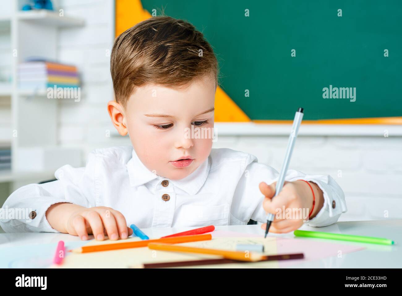Concentrated cute child, writing in notebook using pencil. Cute child ...