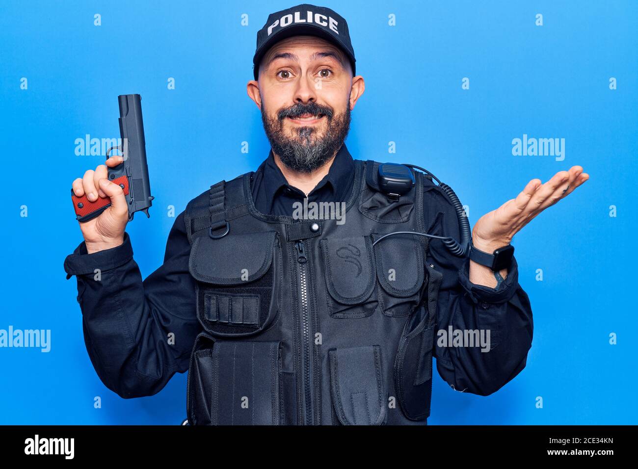 Young handsome man wearing police uniform holding gun celebrating ...